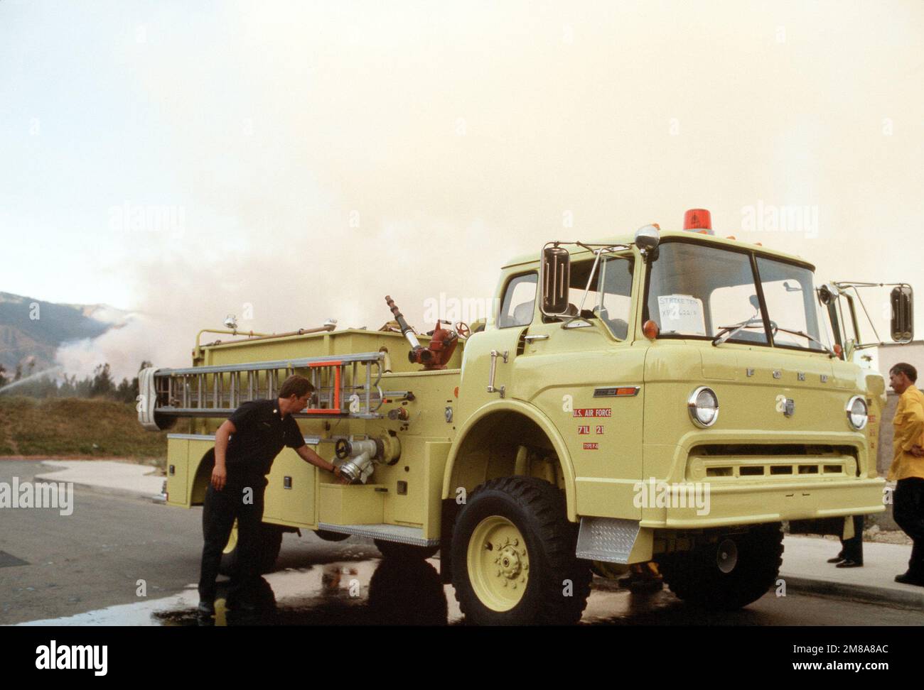 A firefighter opens a filler valve on an Air Force P-8 fire truck ...