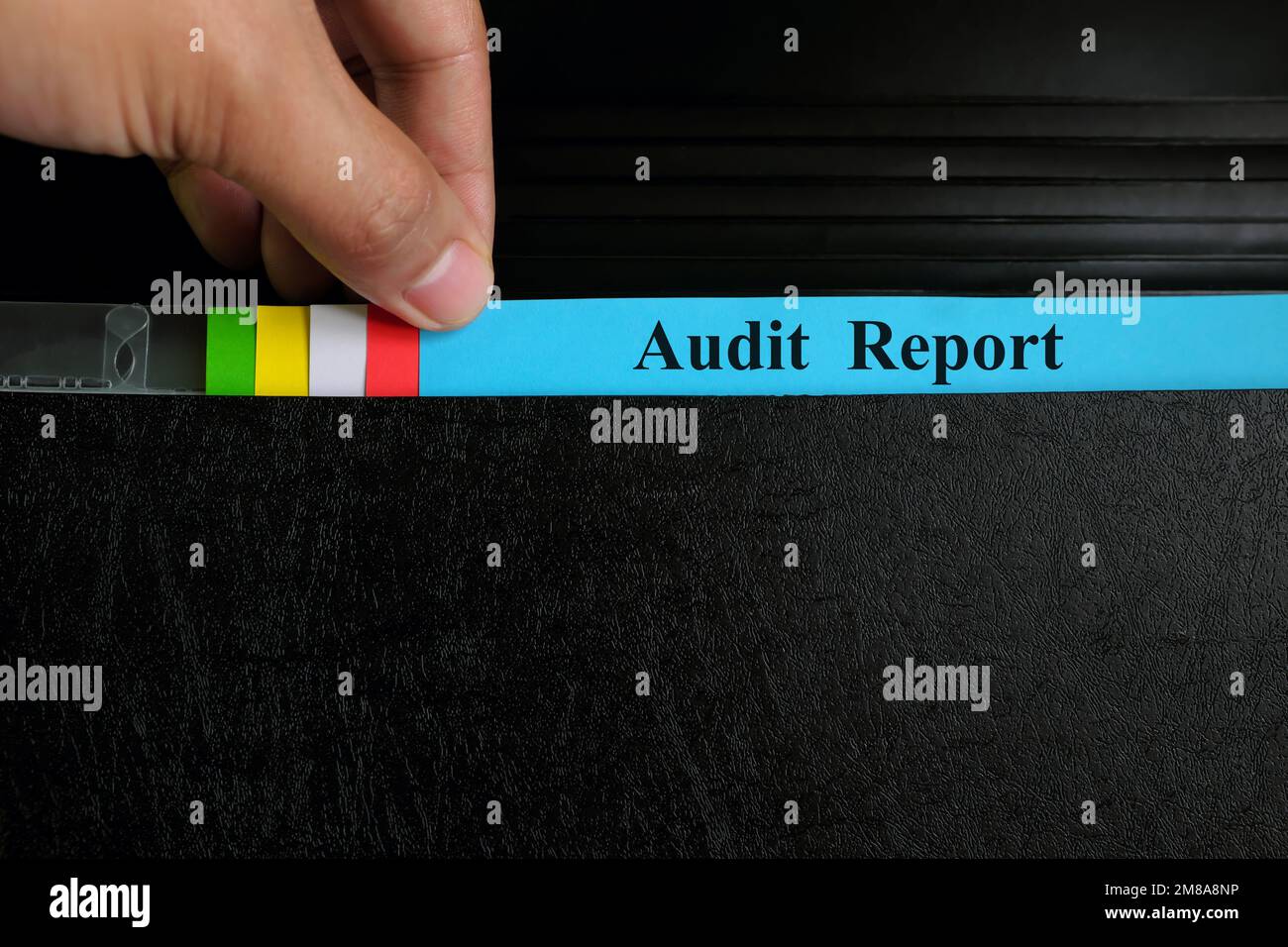 Hand picking audit report file record in black binder folder. Auditing ...