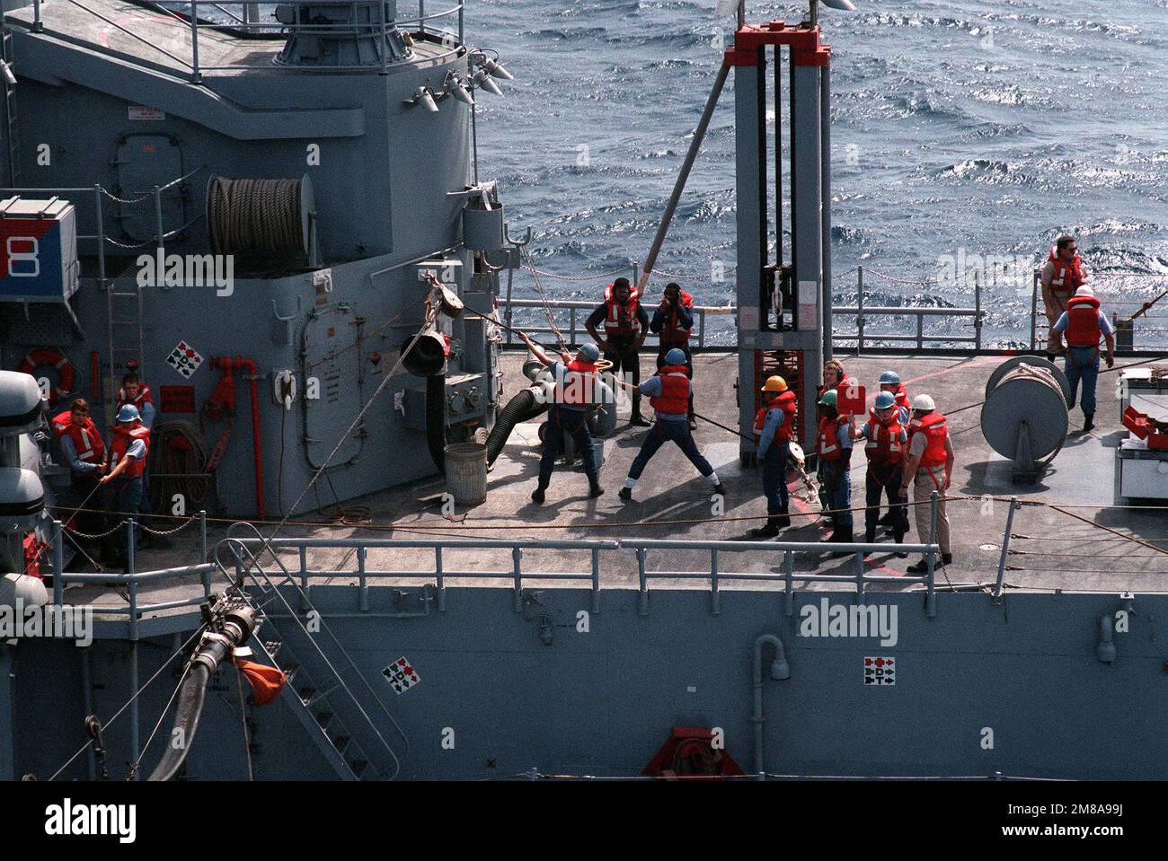 Crewman haul a refueling line aboard the guided missile destroyer USS ...
