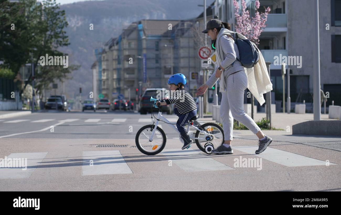Child crossing street in city crosswalk with mother outdoors Stock ...