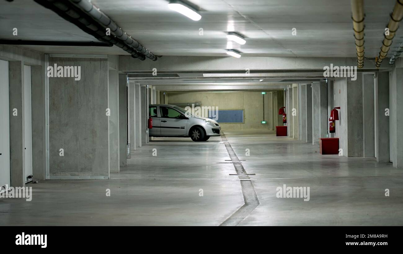 Car exiting underground building parking space in white grey vehicle ...