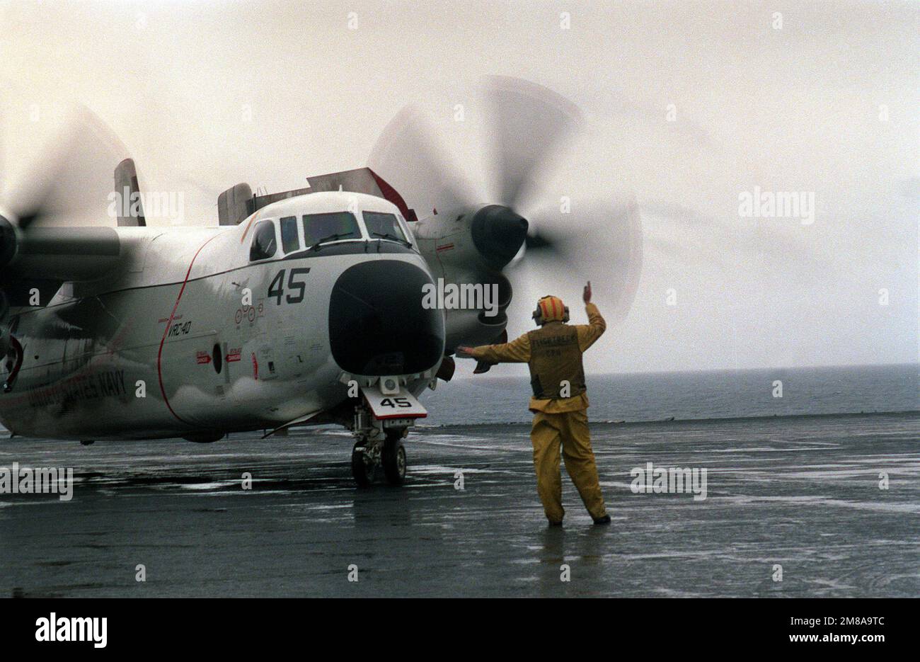 A flight deck crewman signals to the pilot of a Fleet Logistics Support ...
