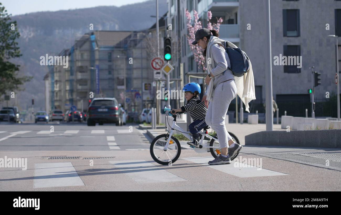Child crossing street in city crosswalk with mother outdoors Stock ...