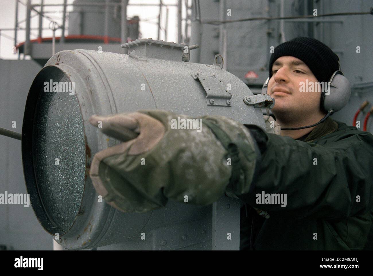 A signalman wearing foul weather gear operates the signaling lever on a ...