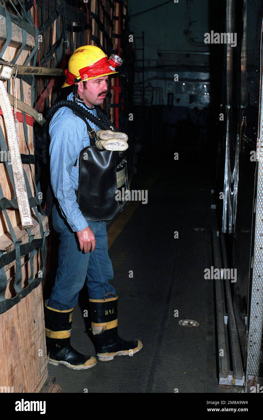 A crewman wears oxygen breathing apparatus aboard the aircraft carrier ...