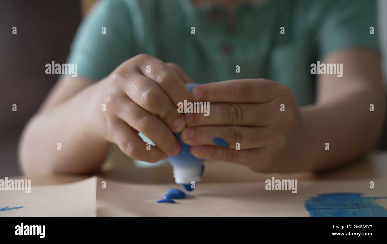 Child hands pressing coloring paint tube. Little boy using creativity ...