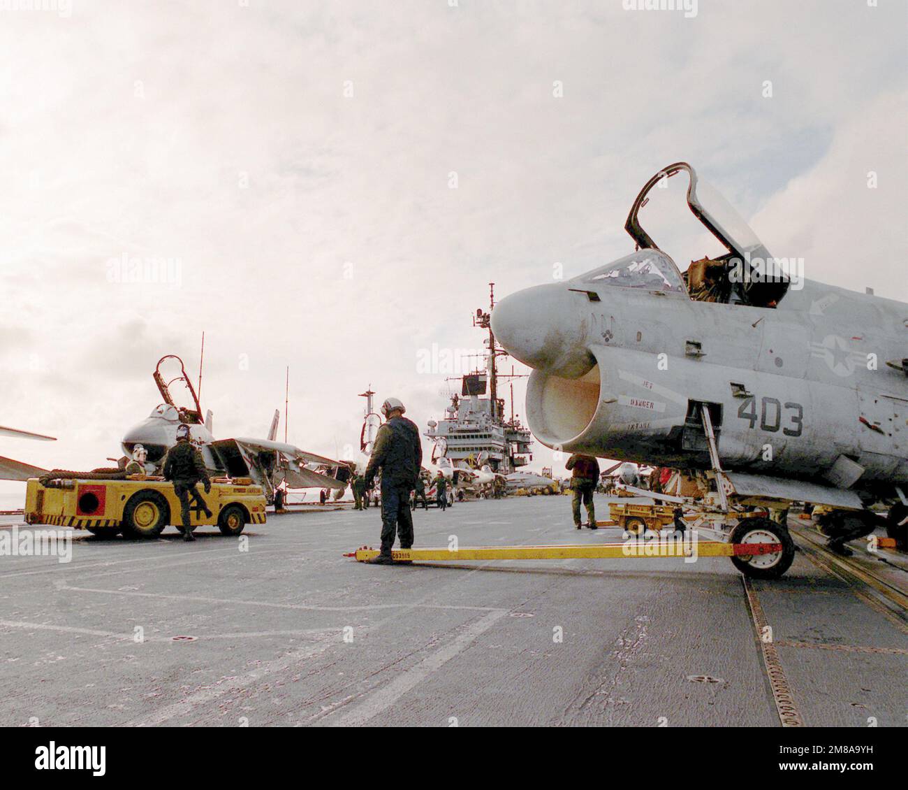 A plane handler straddles a tow bar connected to the nose wheel of an A ...