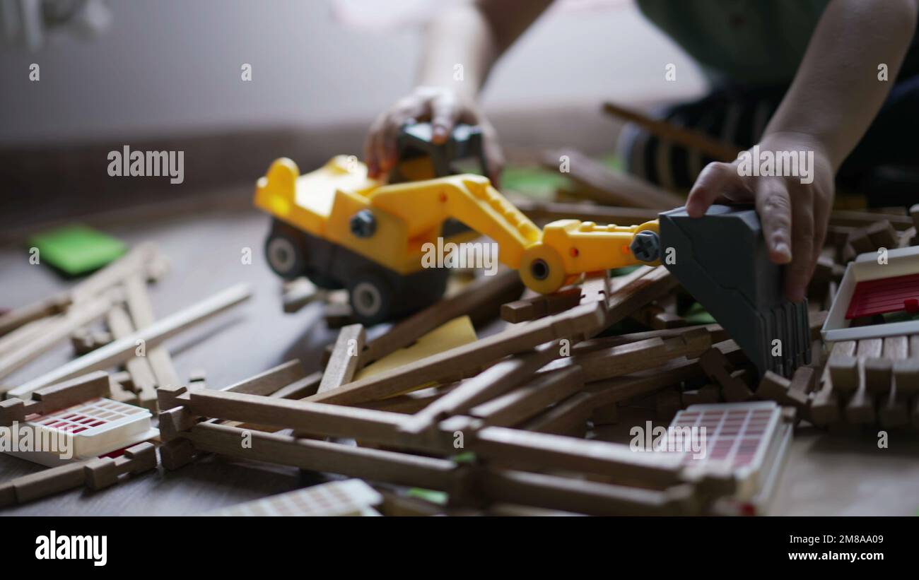 Child destroying wooden home toy with small bulldozer tractor. One ...
