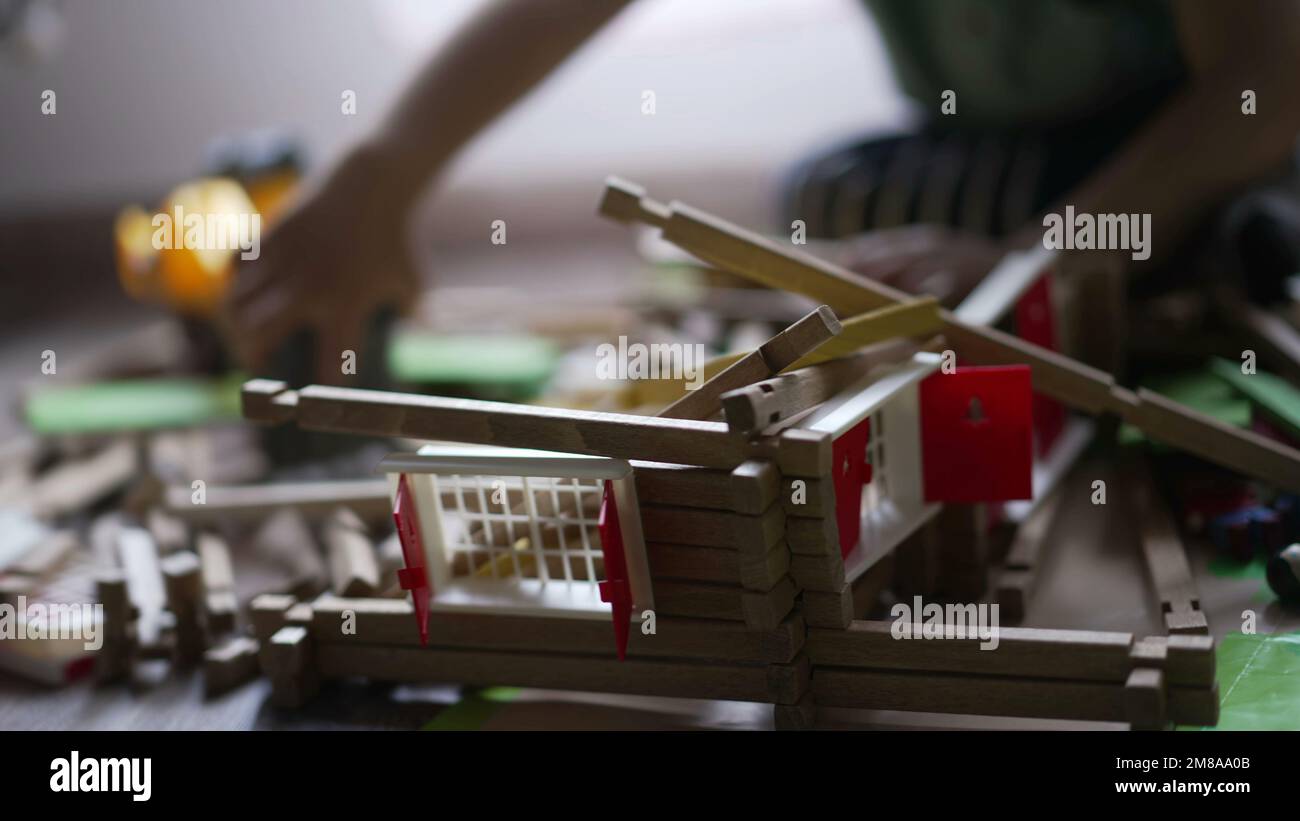 Child destroying wooden home toy with small bulldozer tractor. One ...