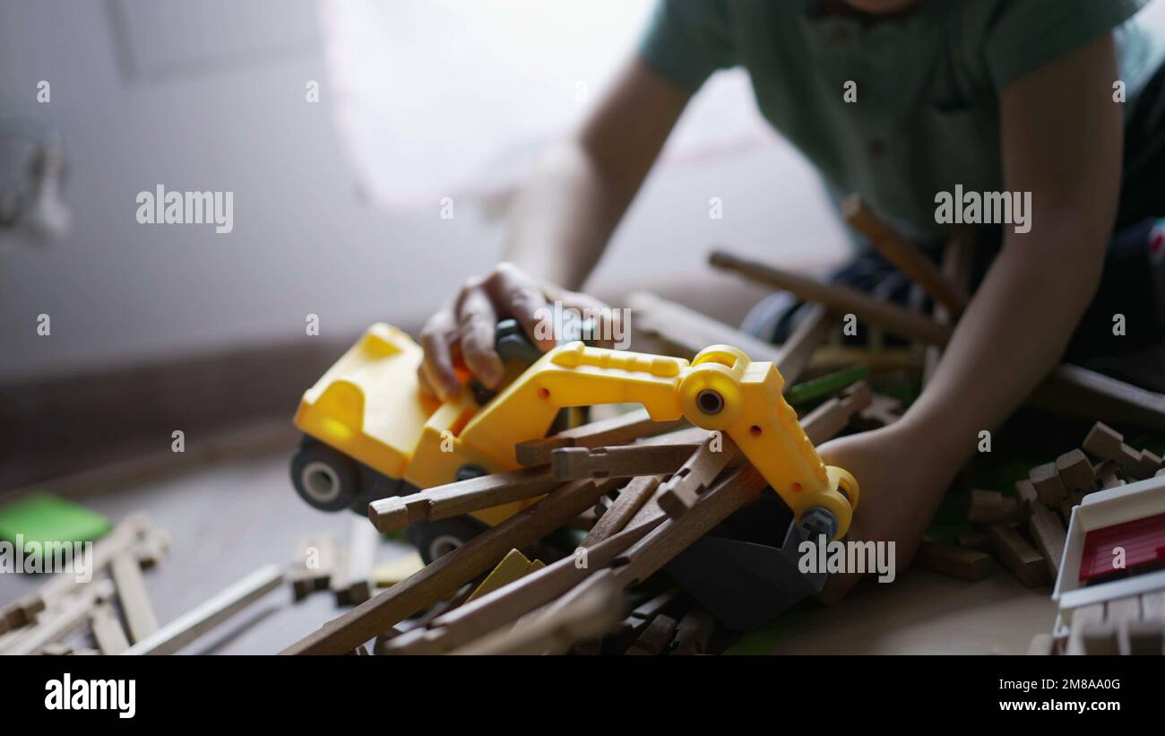 Child destroying wooden home toy with small bulldozer tractor. One ...