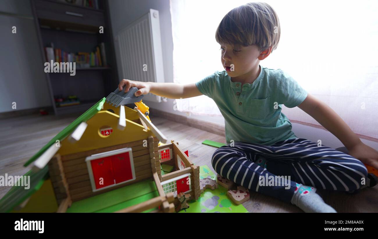 Child playing in room with mother building traditional wooden home toy ...