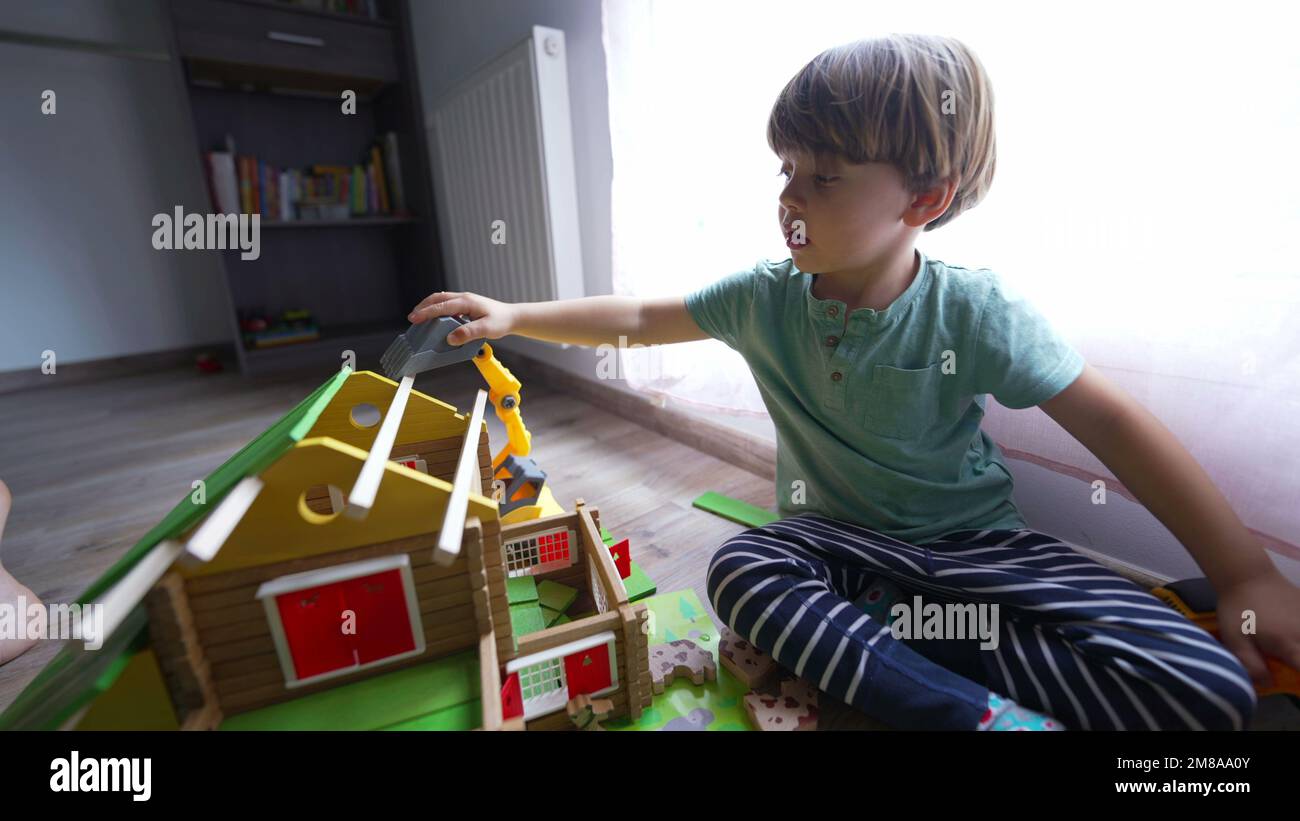 Child playing in room with mother building traditional wooden home toy ...