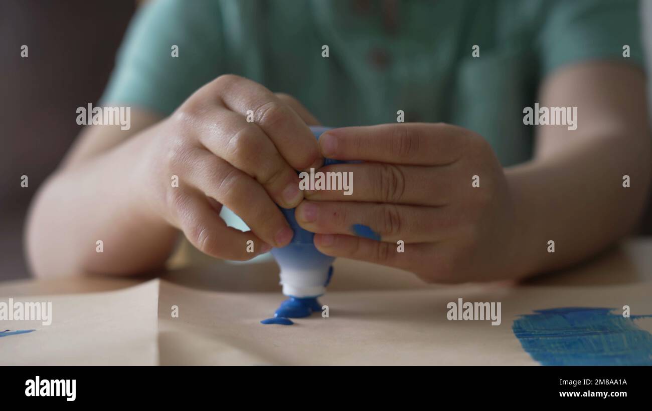 Child hands pressing coloring paint tube. Little boy using creativity ...