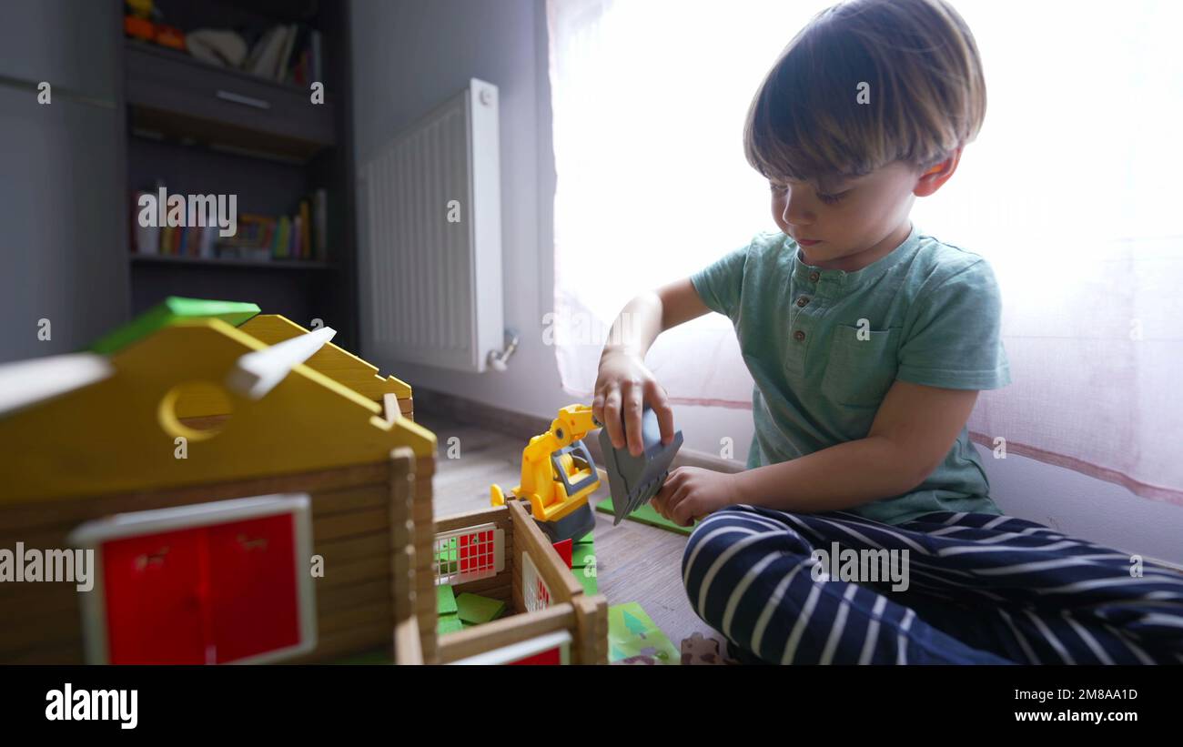 Child playing in room with mother building traditional wooden home toy ...
