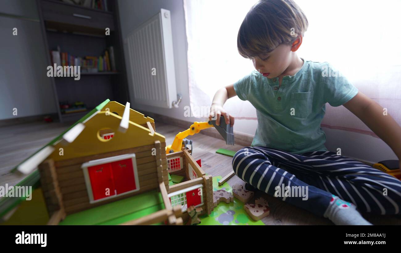 Child playing in room with mother building traditional wooden home toy ...