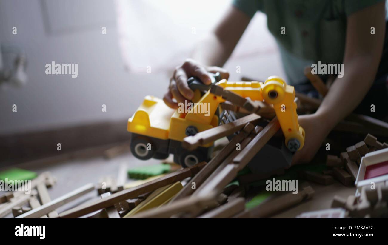 Child destroying wooden home toy with small bulldozer tractor. One ...
