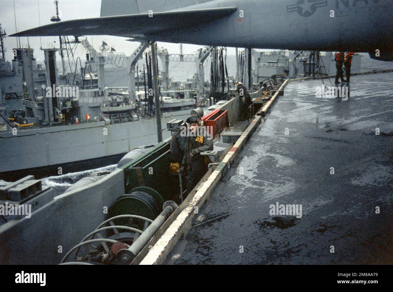 Flight deck crewmen watch from a catwalk aboard the aircraft carrier ...