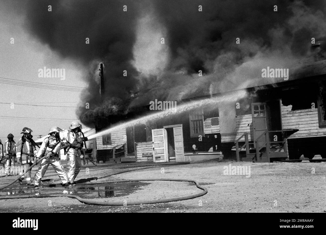 Members of the base fire department extinguish a practice fire set in ...