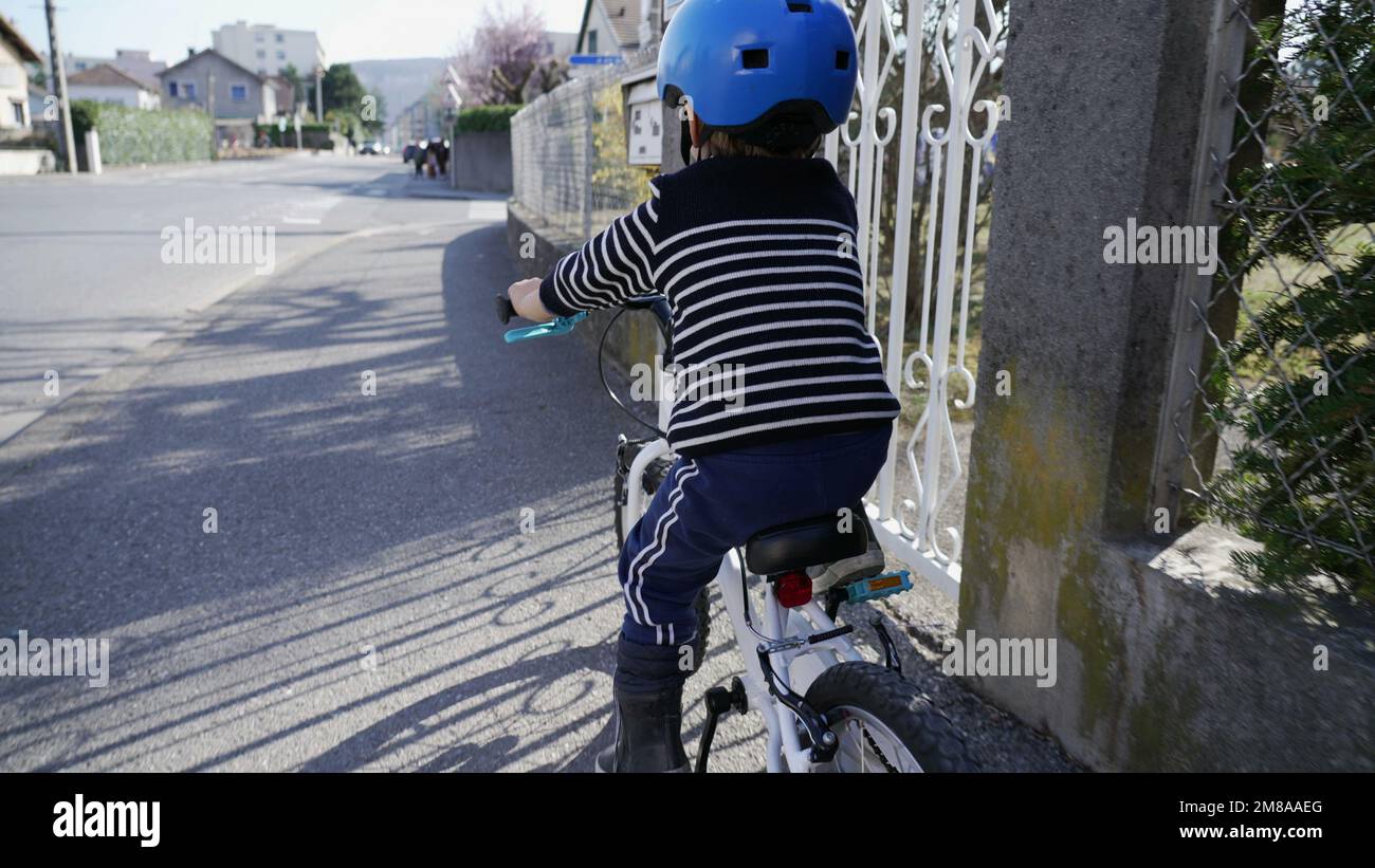 Child riding bicycle outside wearing coat and helmet. One little boy ...