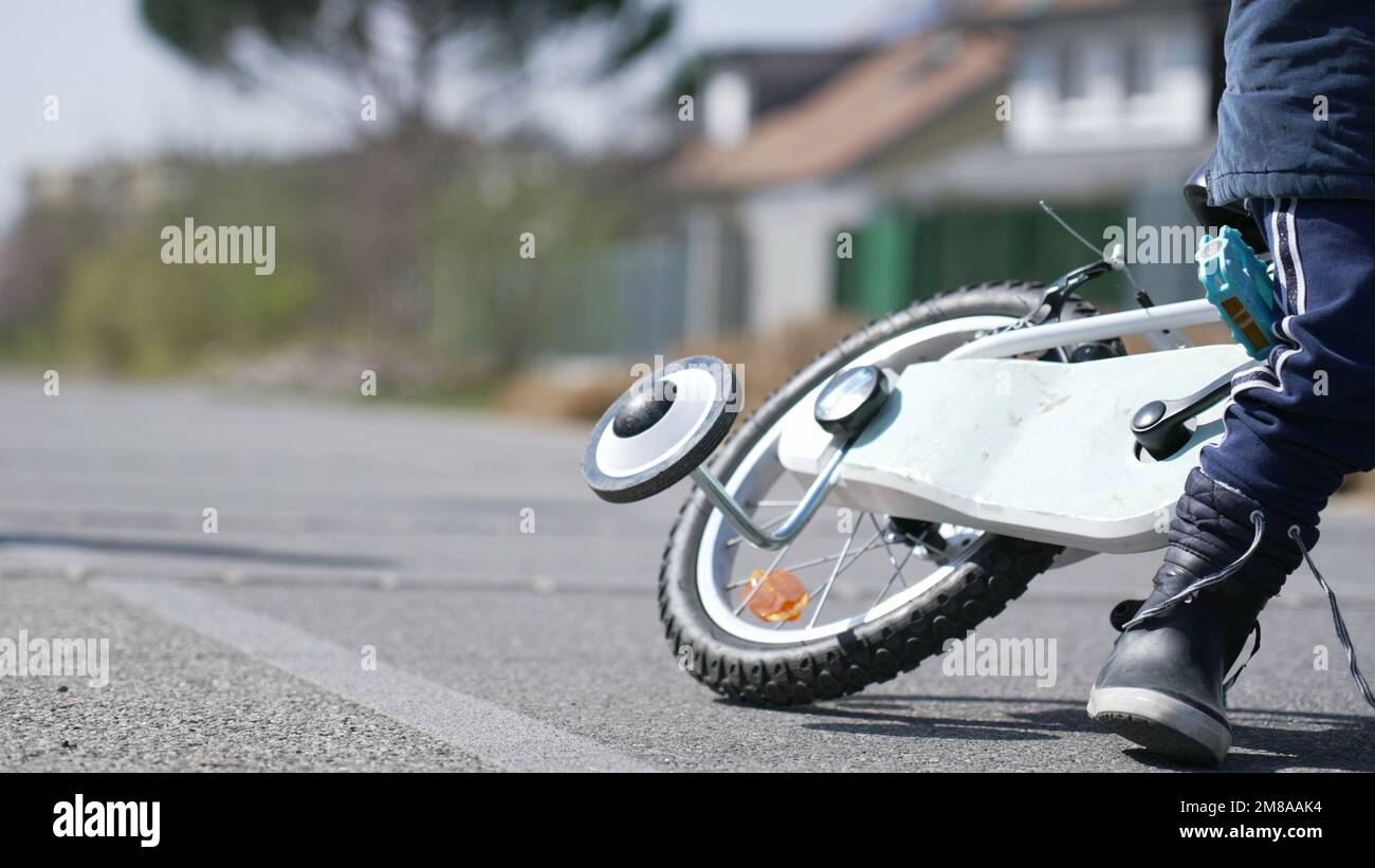 Closeup child feet falling from bicycle outside. Kid learns to ride ...