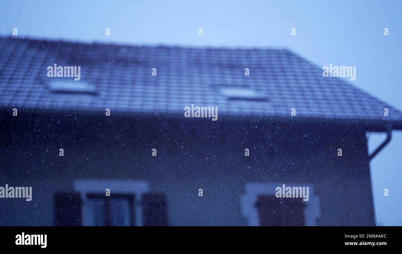 Falling snow closeup of house rooftop during winter season. Traditional ...
