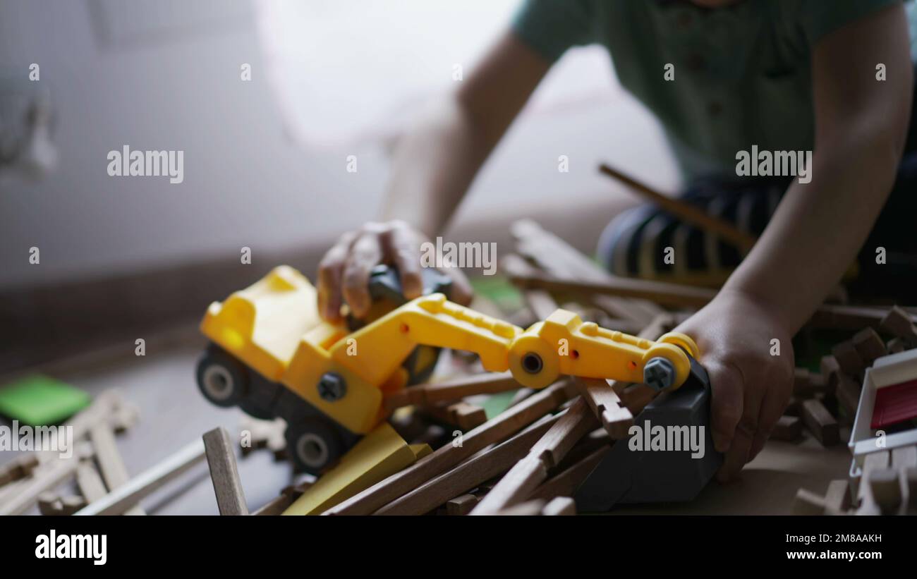 Kid plays with bulldozer tractor toy picking pieces of wood playing at ...