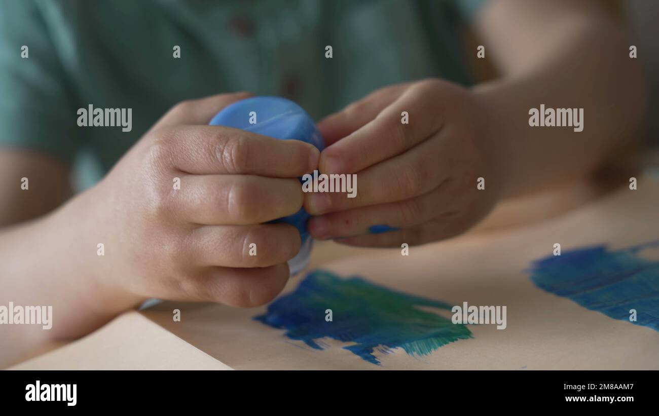 Little boy hands pressing coloring paint tube on paper. Child using ...