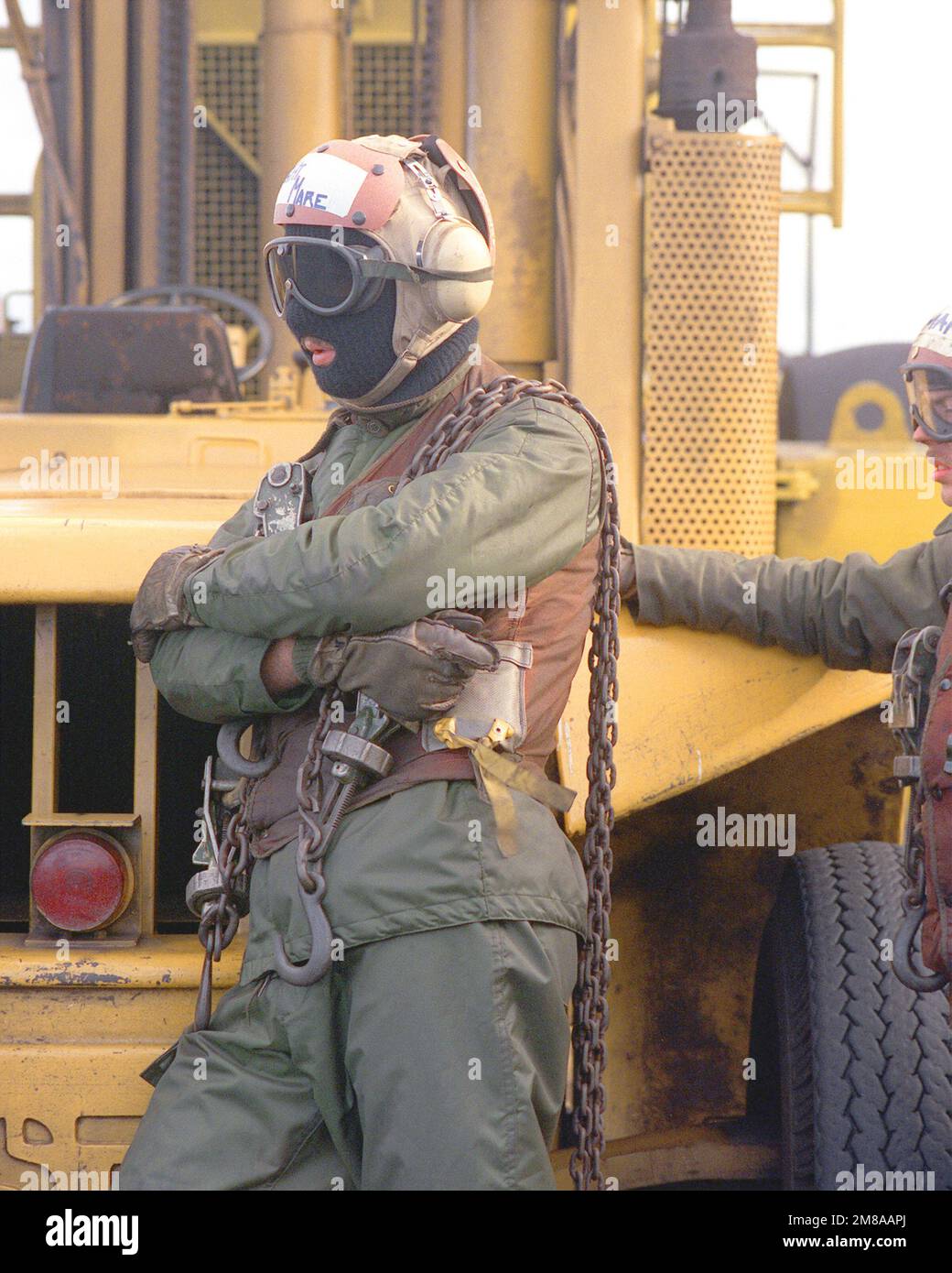 A flight deck crewman dressed against the cold stands by with a set of ...
