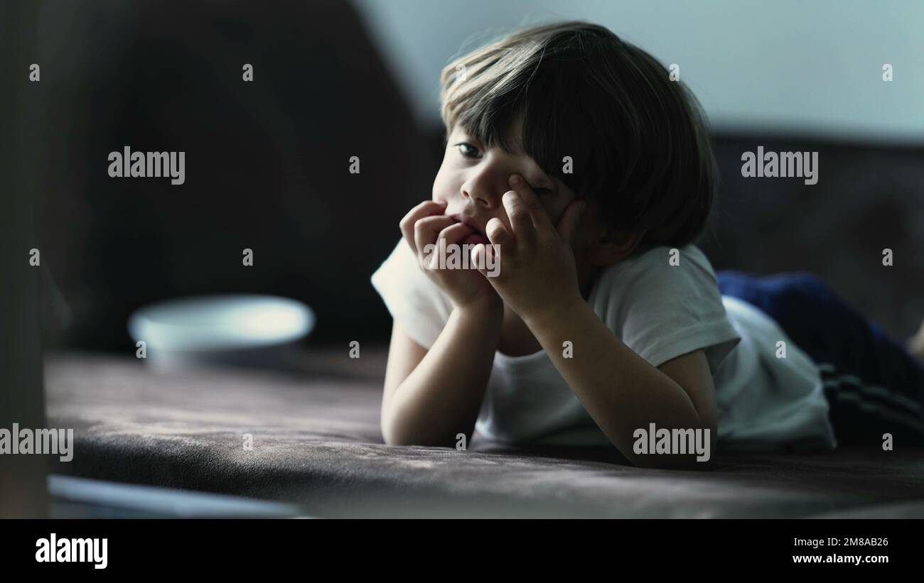 One bored small boy watching screen at home on couch. Child touching ...