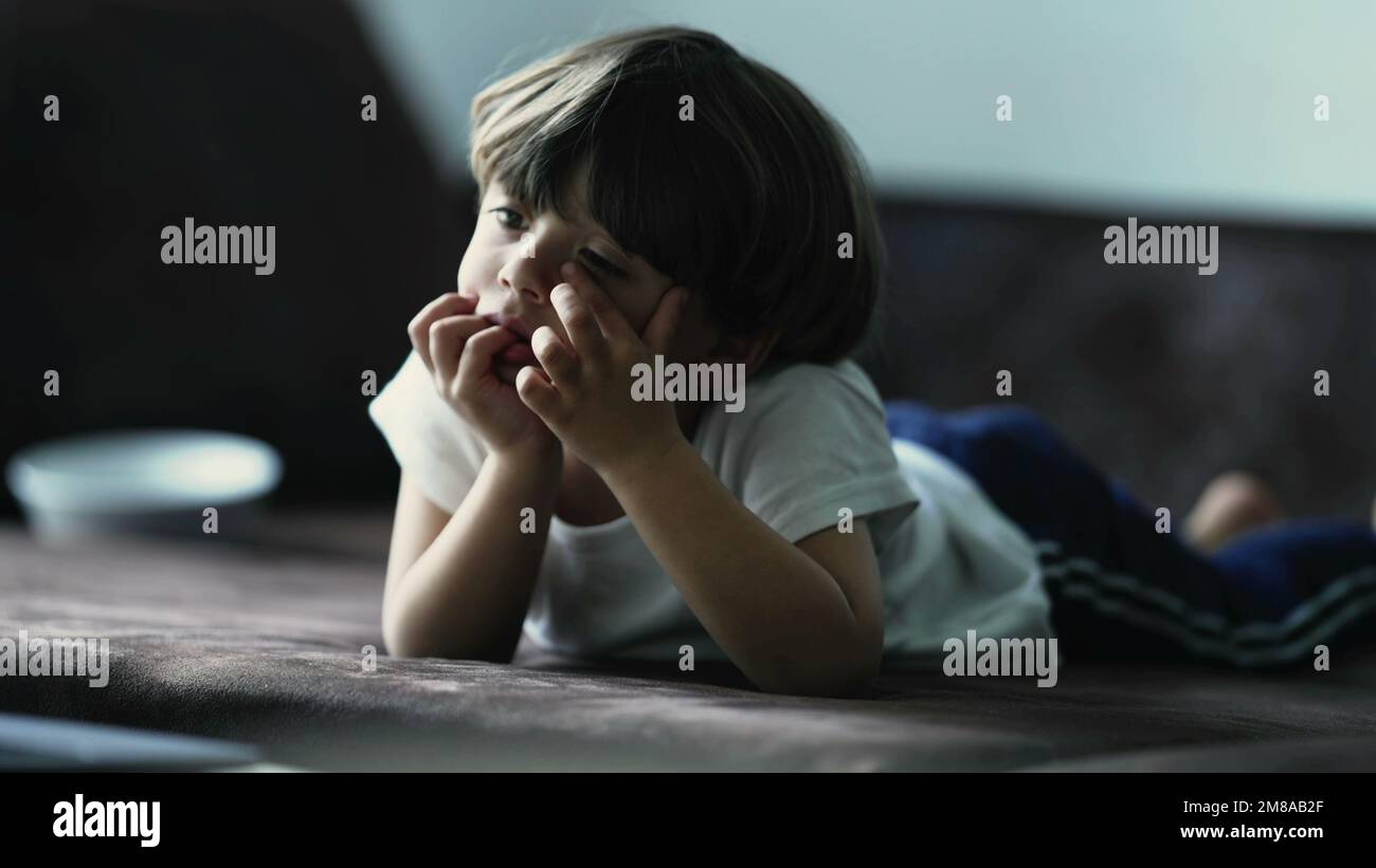 One bored small boy watching screen at home on couch. Child touching ...