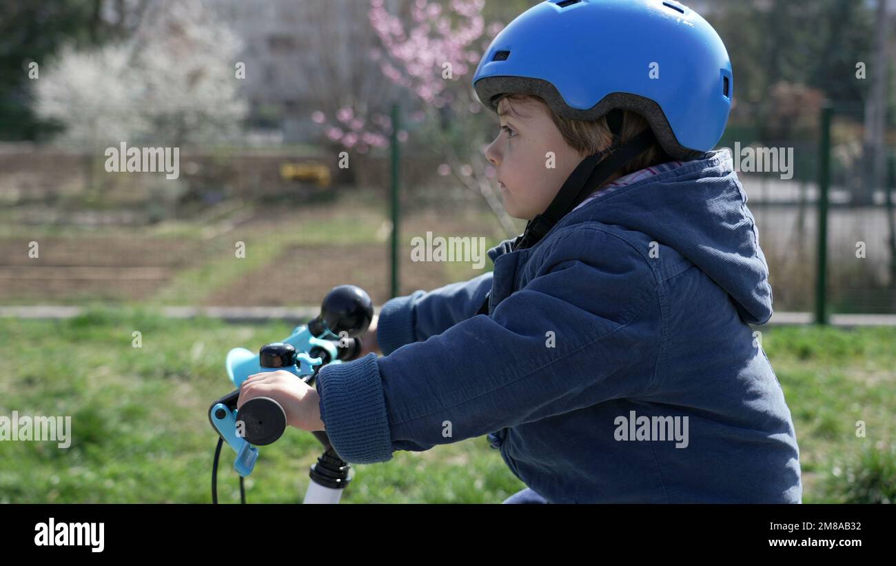 One little boy cyclist riding bicycle outdoors wearing helmet ...