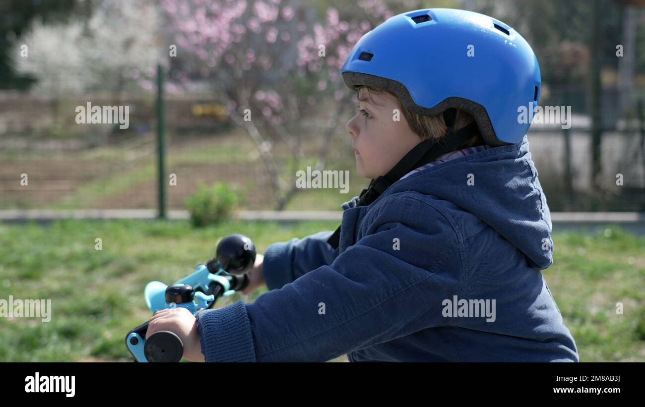 One little boy cyclist riding bicycle outdoors wearing helmet ...