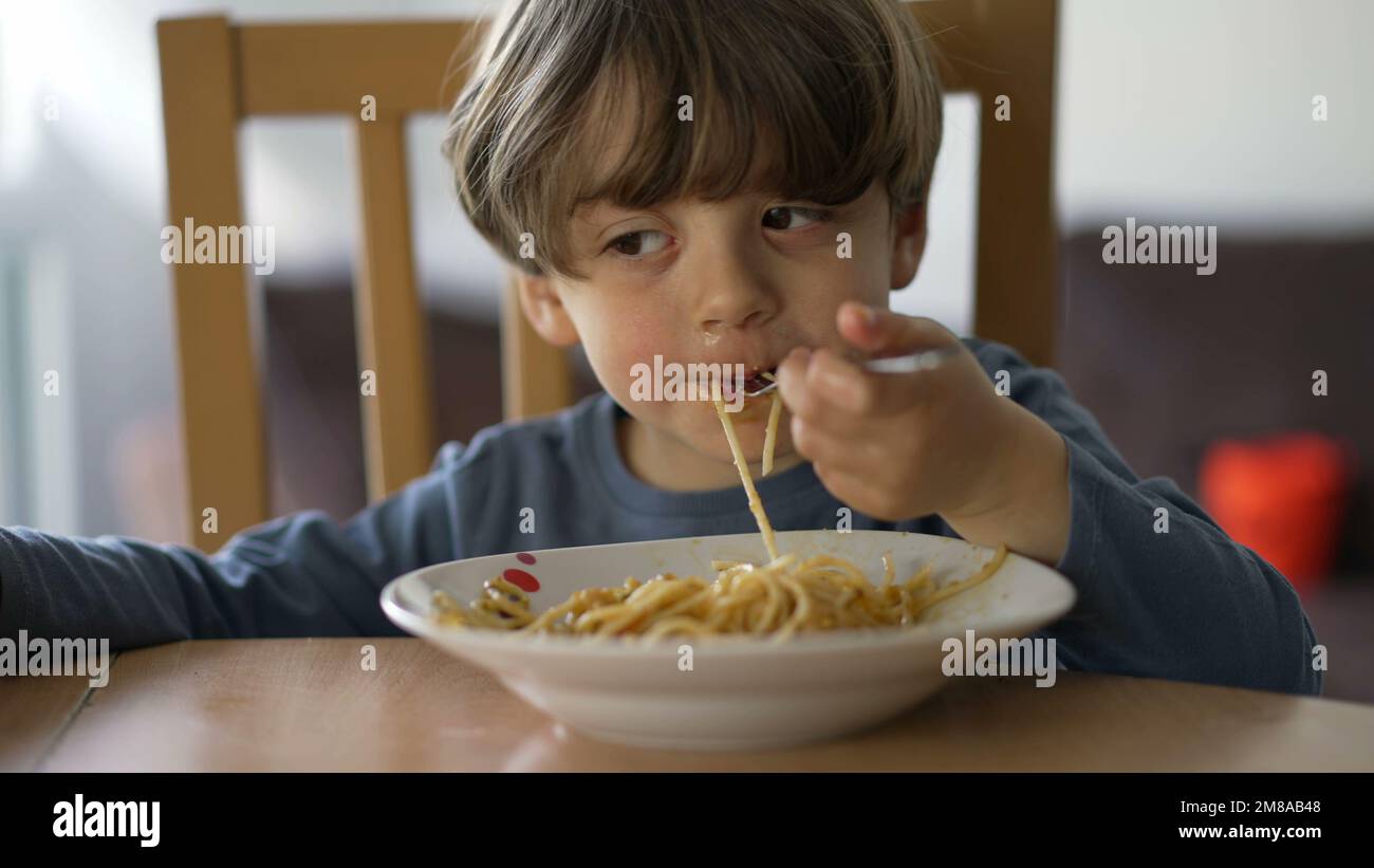 One little boy eating pasta with fork. Child eats lunch meal carb food ...