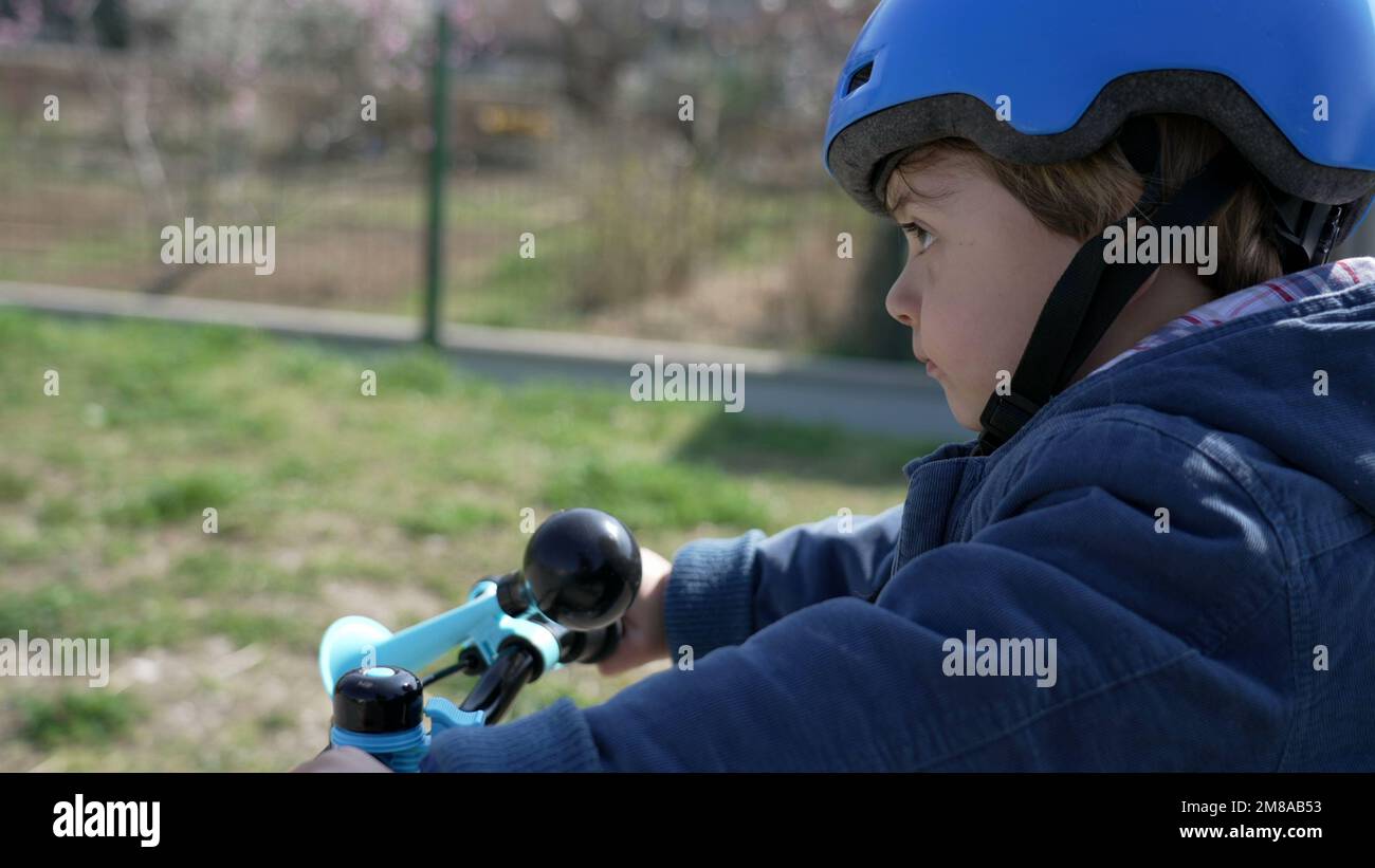 One little boy cyclist riding bicycle outdoors wearing helmet ...