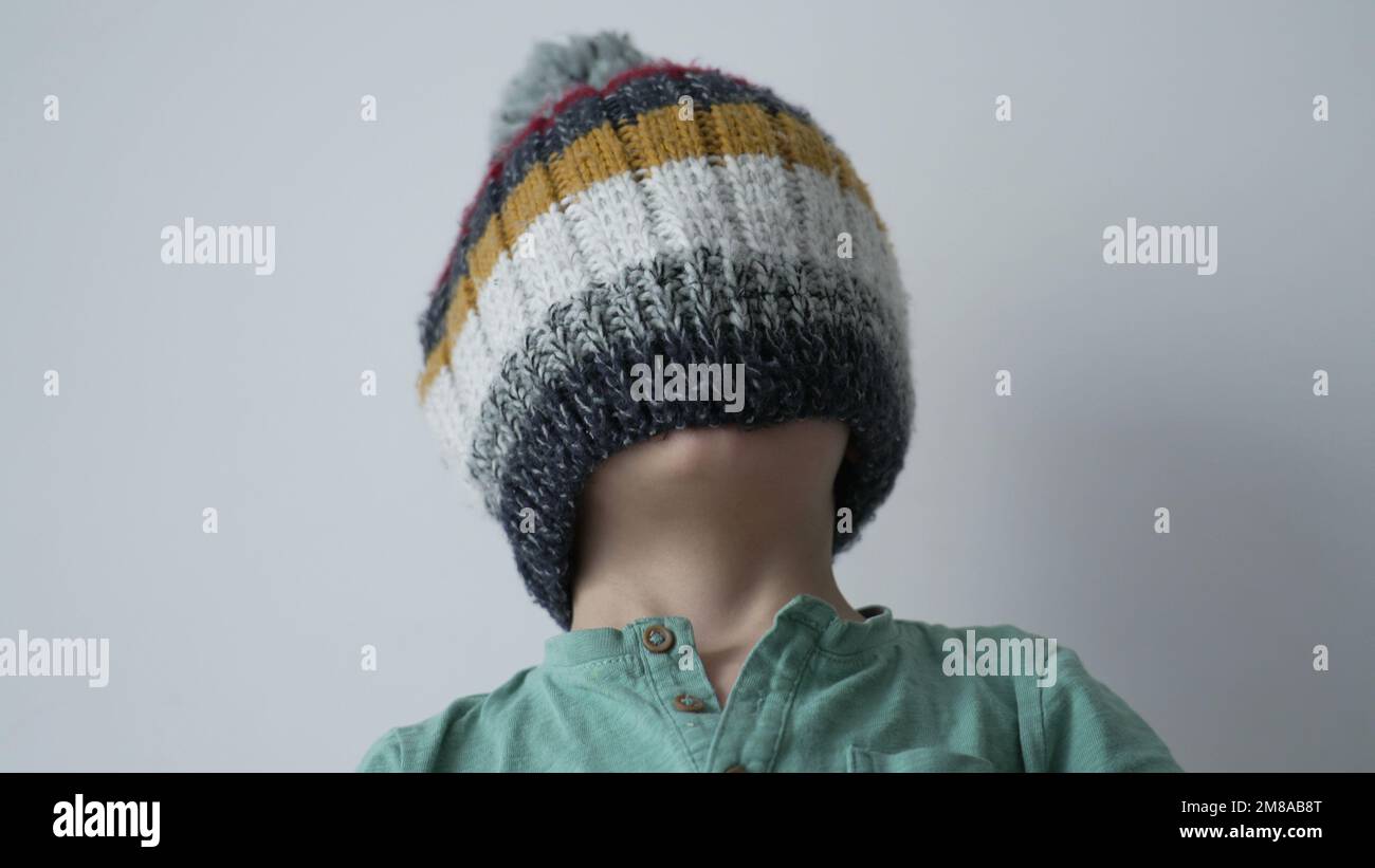 One little boy putting beanie covering face. Funny child wearing wool ...