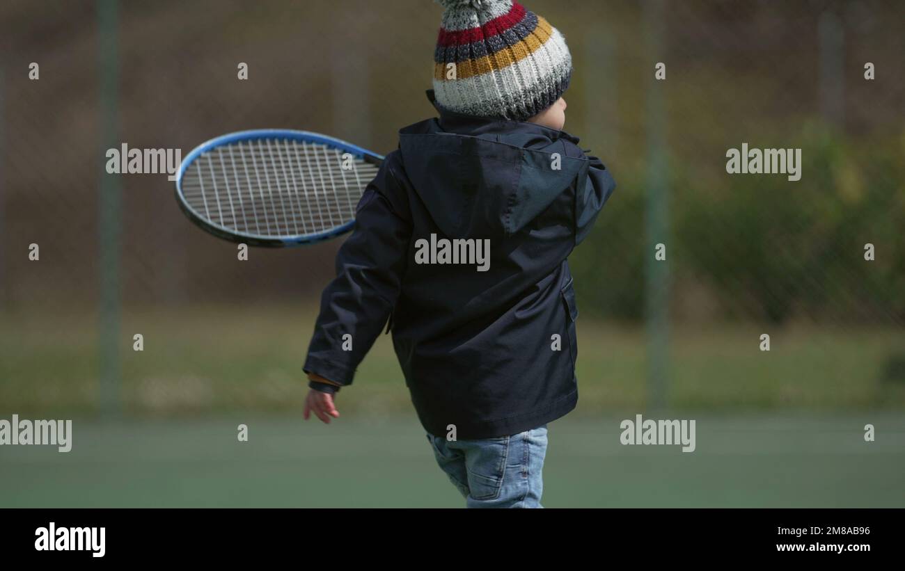 One little boy holding tennis racket playing outside Stock Photo - Alamy