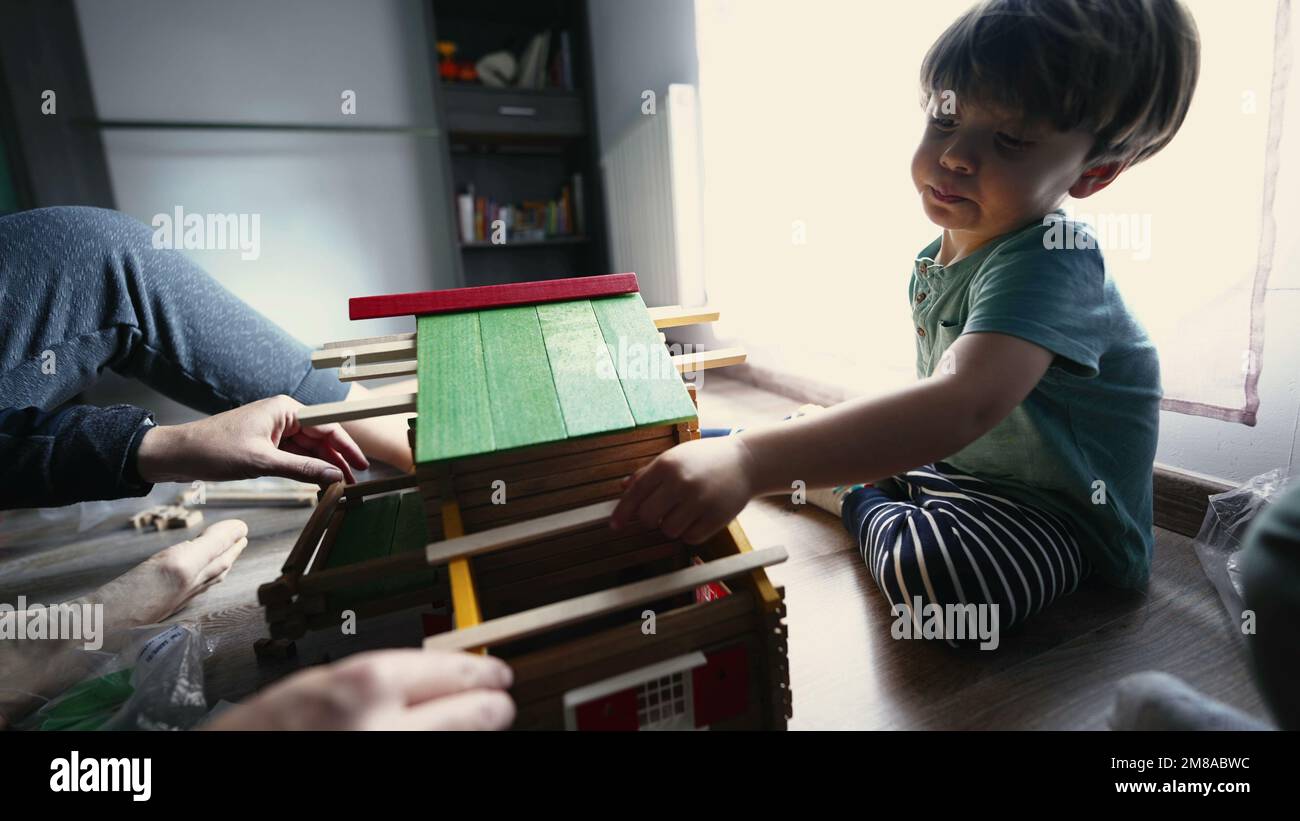 Child building wooden house toy in playroom. One little boy putting ...