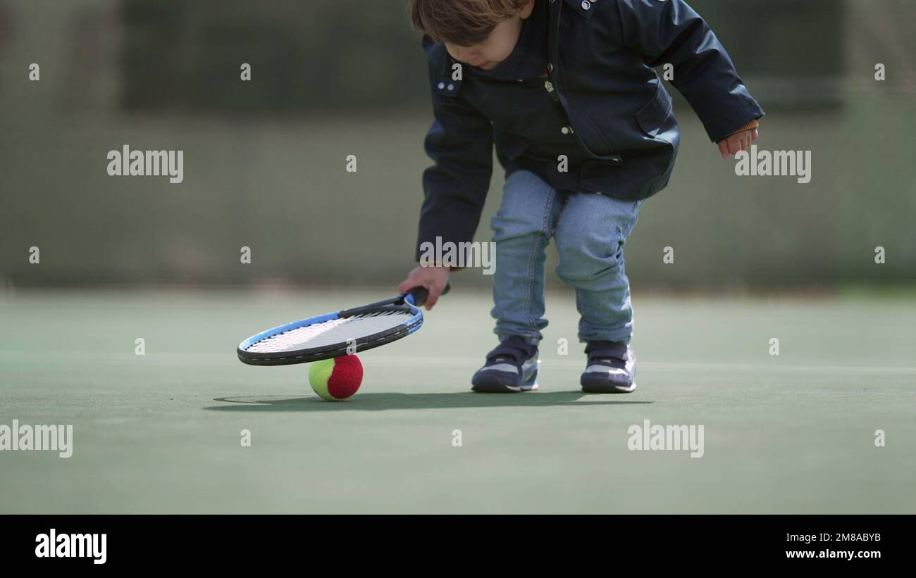 Child stopping tennis ball with racket outdoors wearing winter coat ...