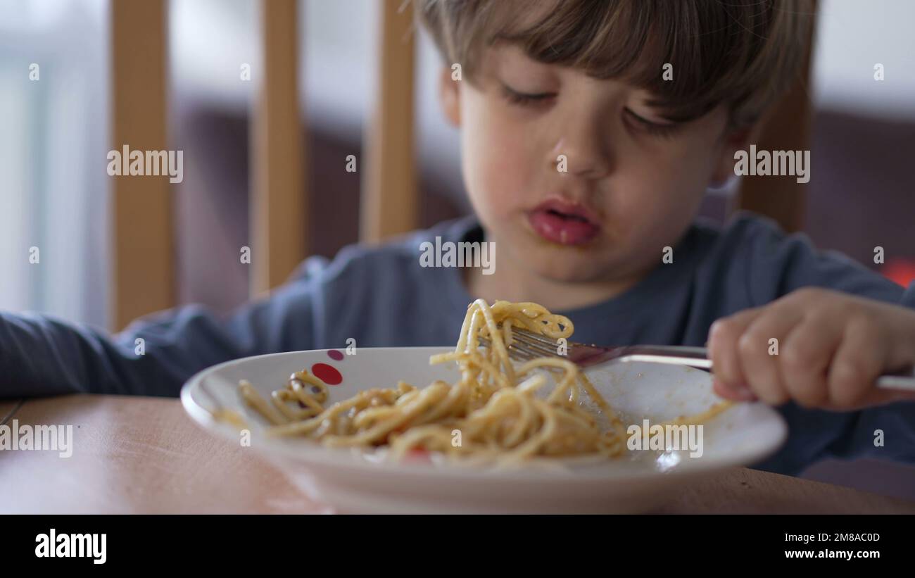 One little boy eating pasta with fork. Child eats lunch meal carb food ...