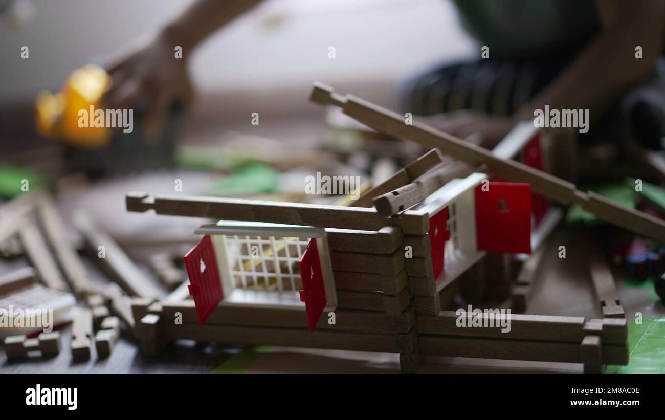 One small boy destroying wooden house toy with tractor bulldozer. Child ...