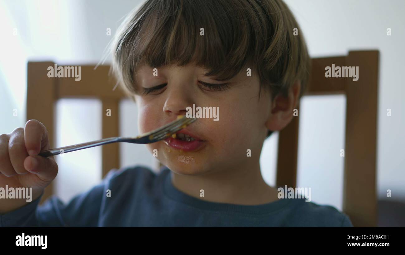 Closeup child face eating pasta. One blond make kids eats noodles ...