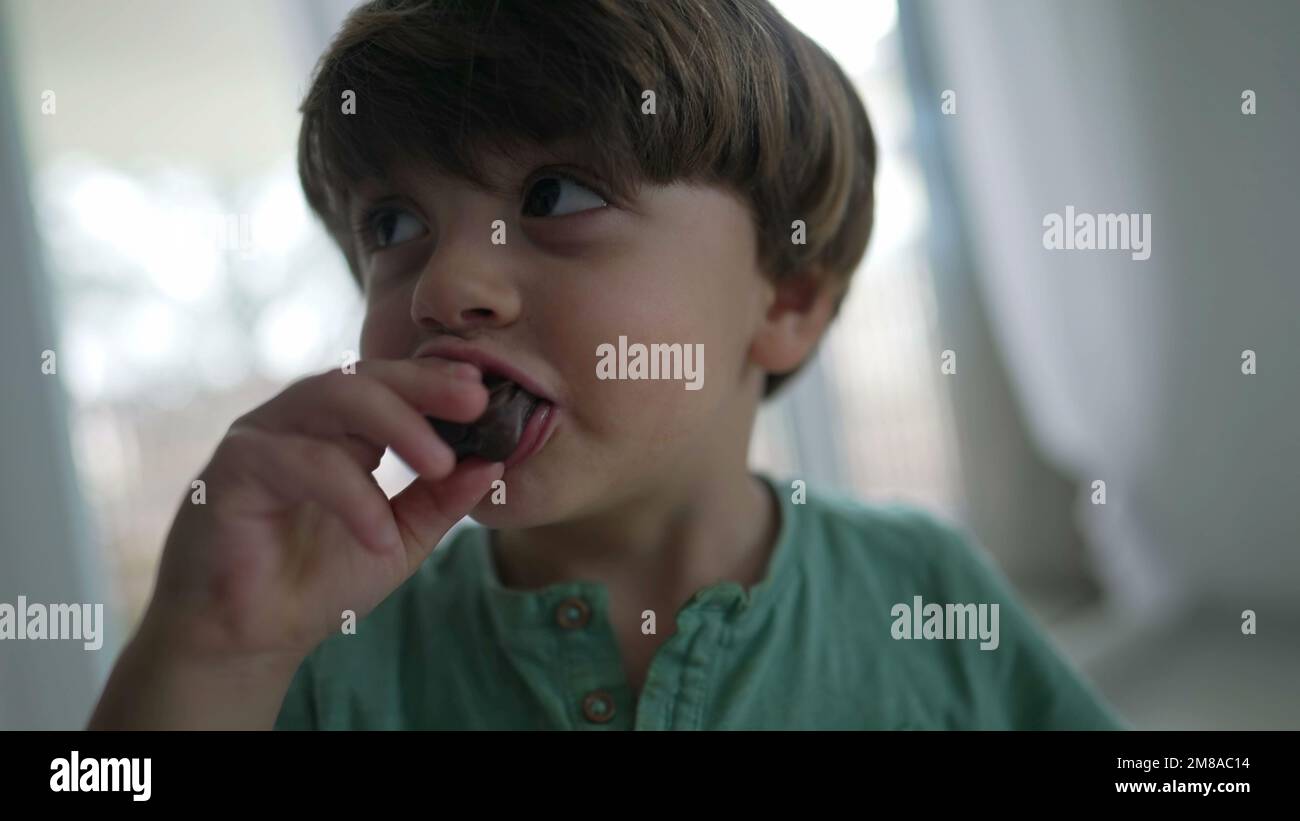 One happy child eating chocolate. Little boy eats sweet dessert closeup ...