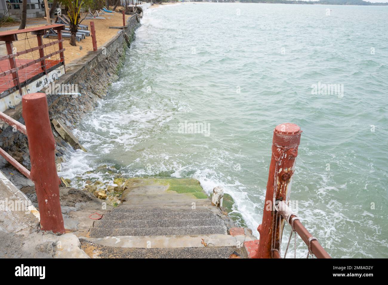 Steps to the sea at high tide with very little beach in strong wind and ...