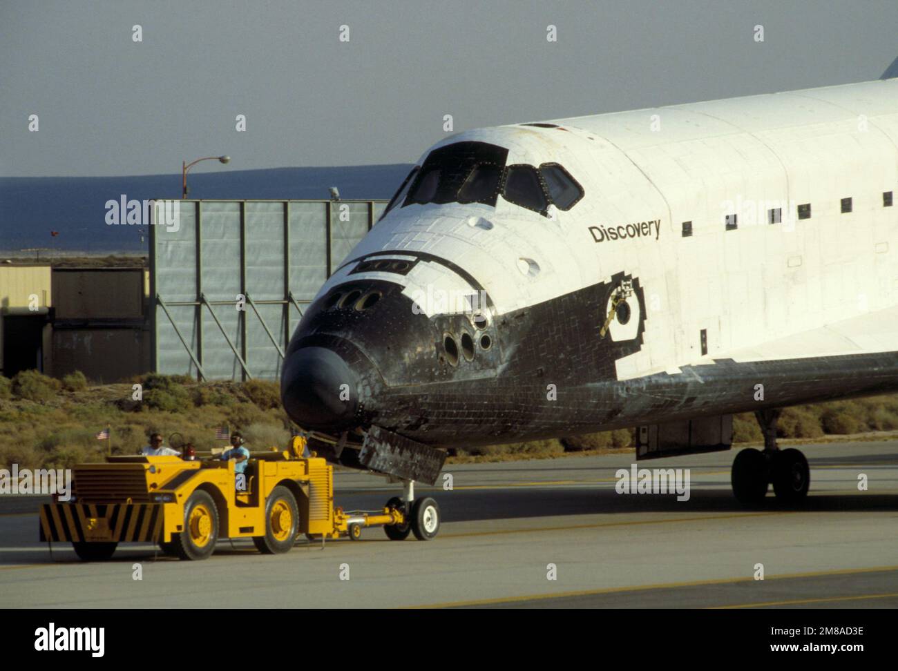 Support personnel driving a T-300 tow tractor pull the space shuttle ...