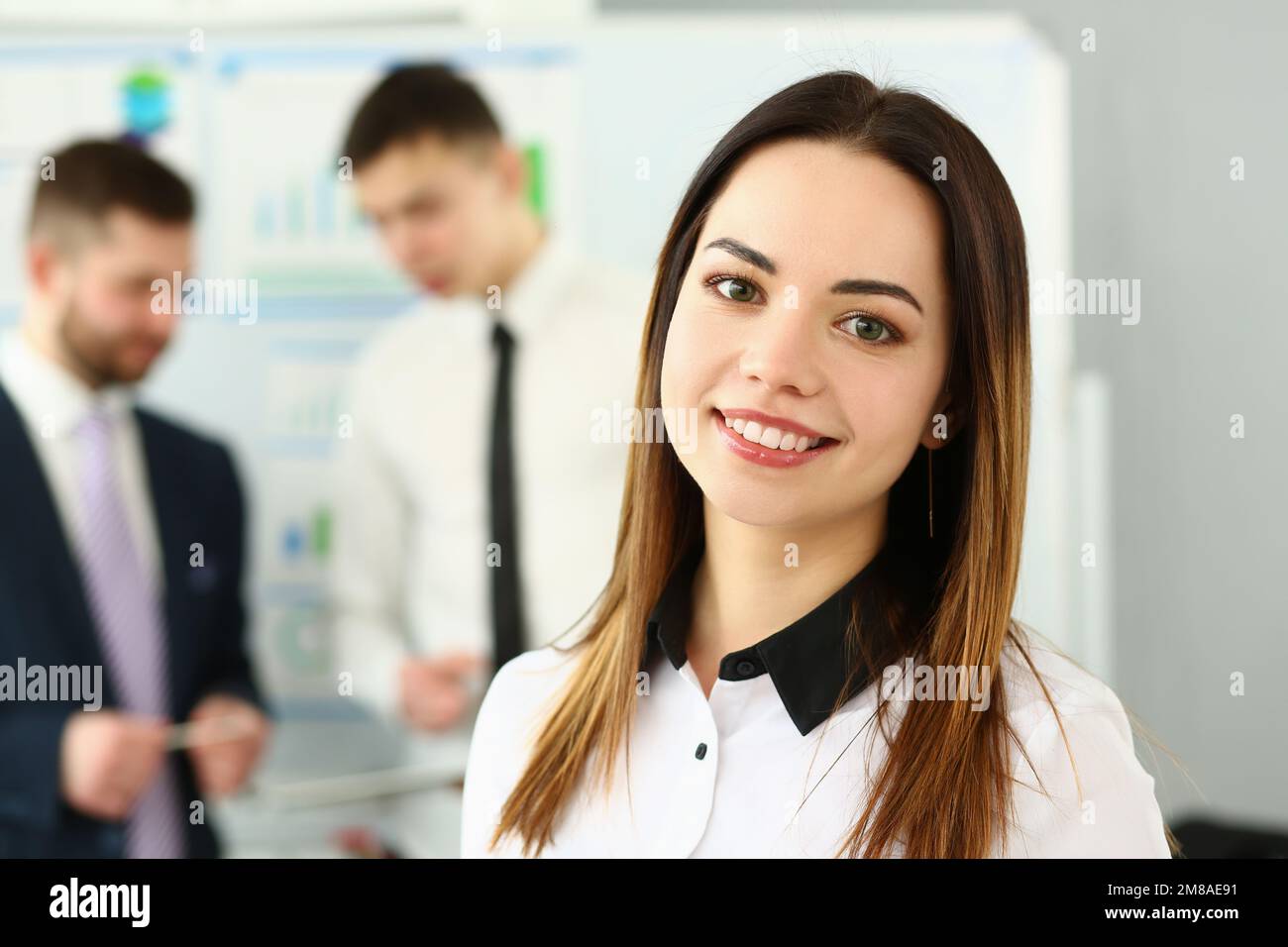 Successful business woman standing with employees in background in ...