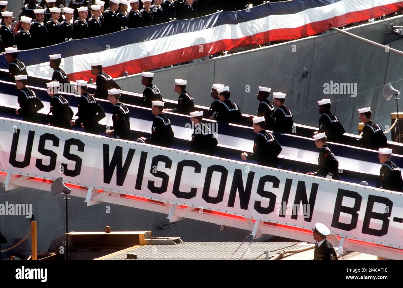Members of the crew file aboard the battleship USS WISCONSIN (BB 64) as ...