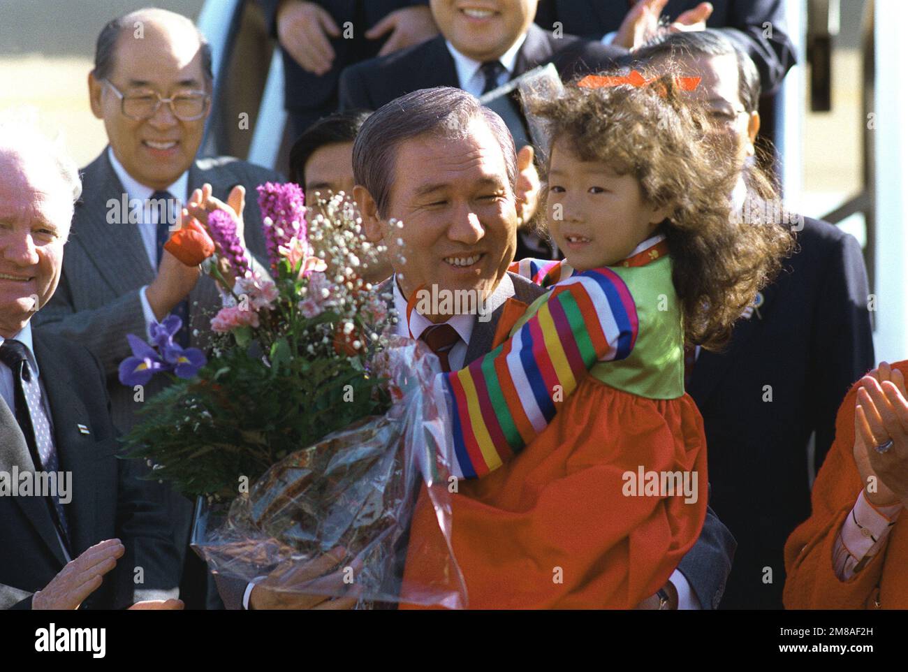 President Roh Tae Woo of South Korea holds a child after accepting her bouquet of flowers upon ...