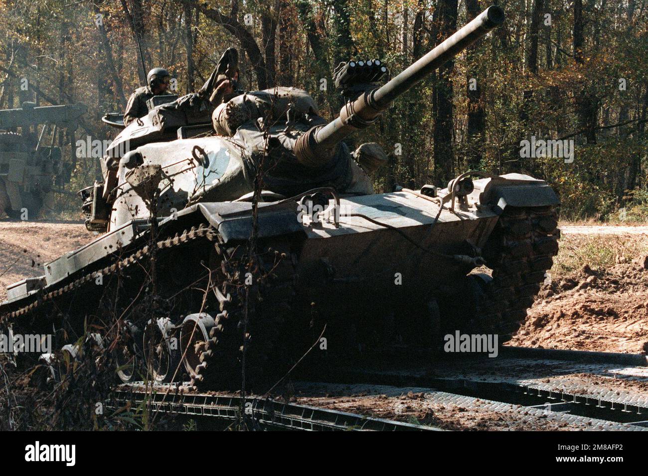 A Marine M-60 tank begins moving up onto a floating bridge from a dirt ...