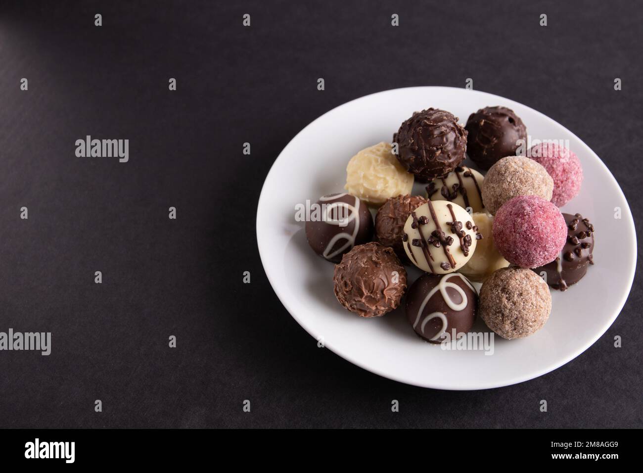 A photo of many different chocolates lying in a white round plate Stock ...