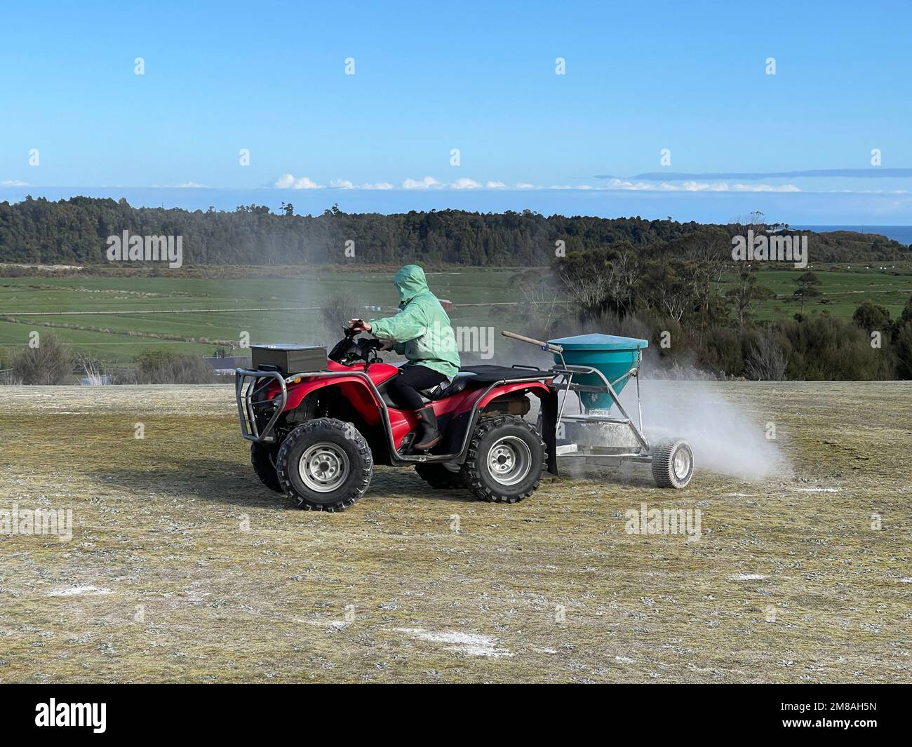 A quad bike spraying Lime seeds on an agriculture field with green ...